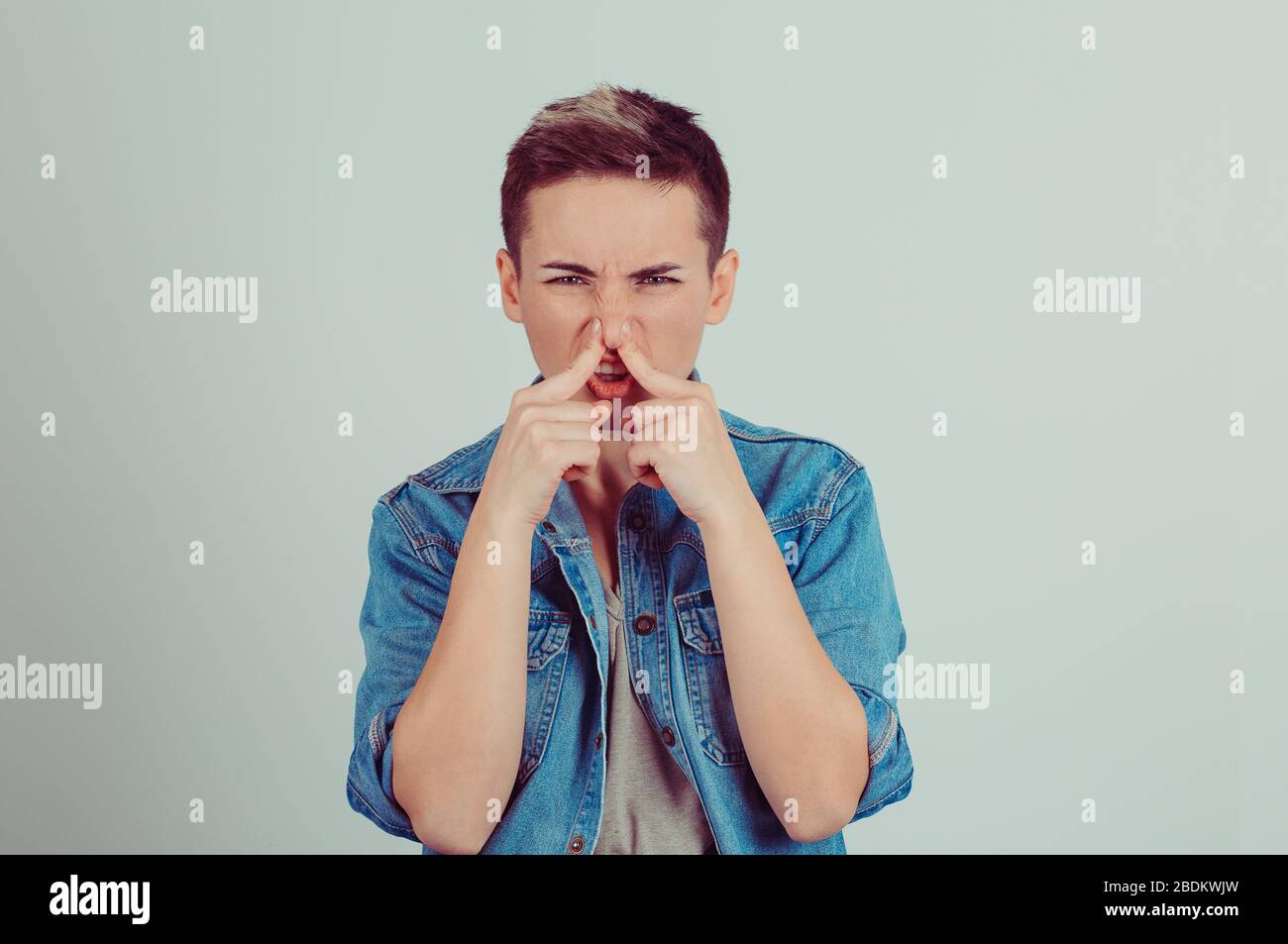 headshot woman pinches nose with fingers hand looks with disgust away ...