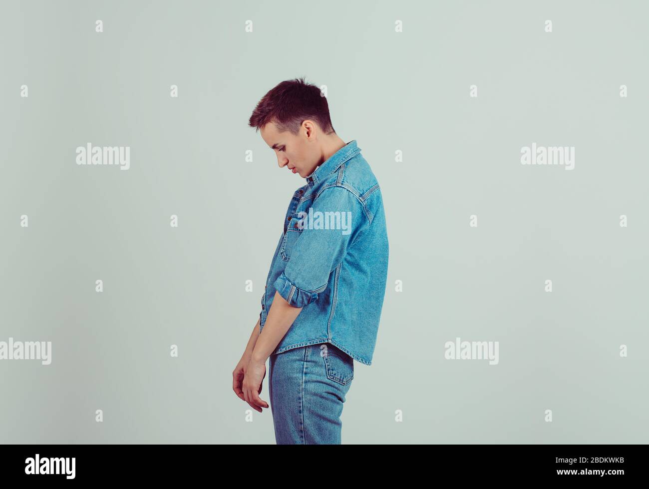 Side profile sad lonely young woman looking down isolated on gray green ...