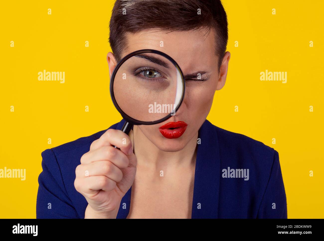 Skeptical woman looking through magnifying glass isolated yellow wall ...
