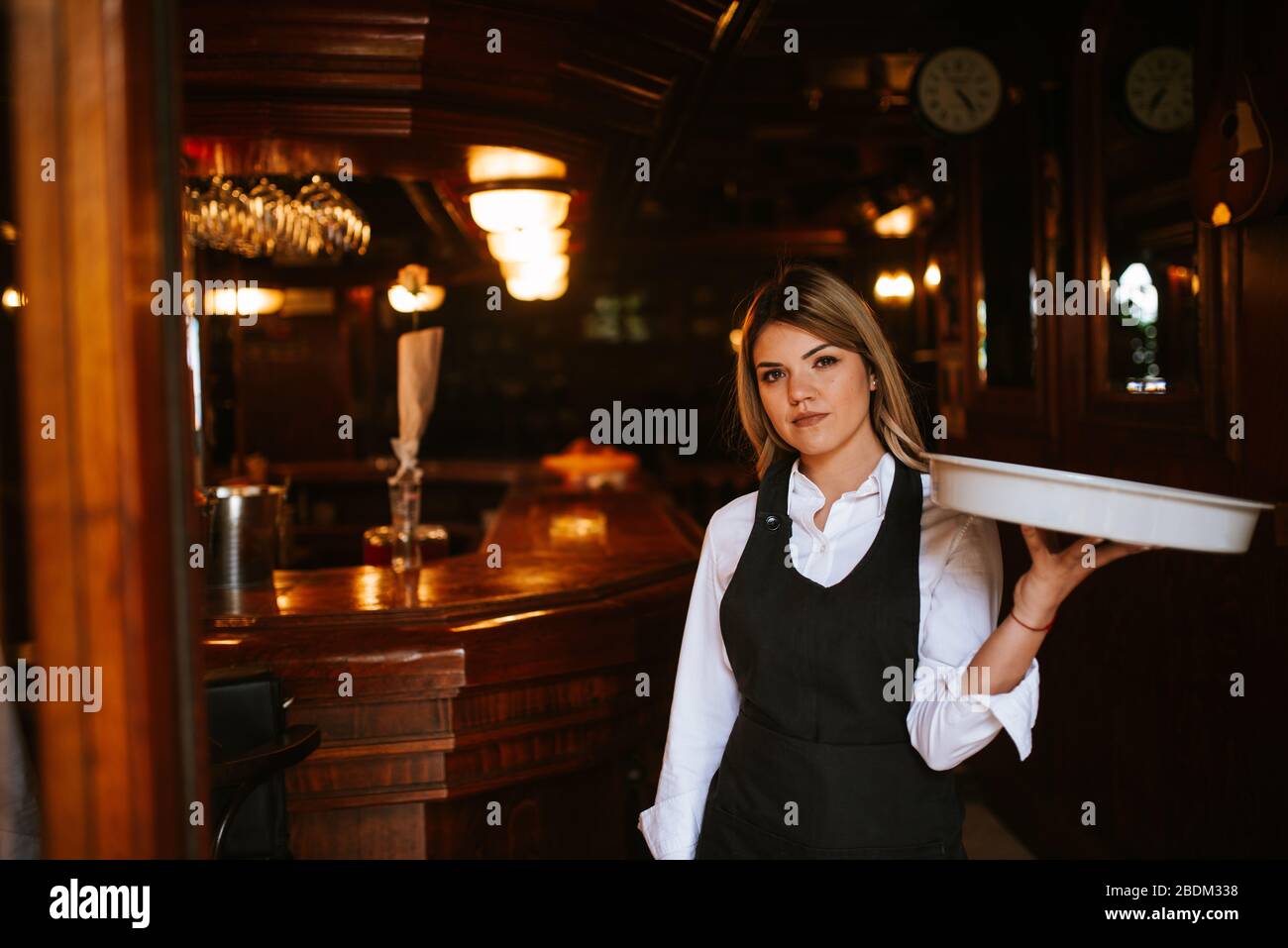 A young attractive blonde caucasian waitress with a tray in a cafe ...