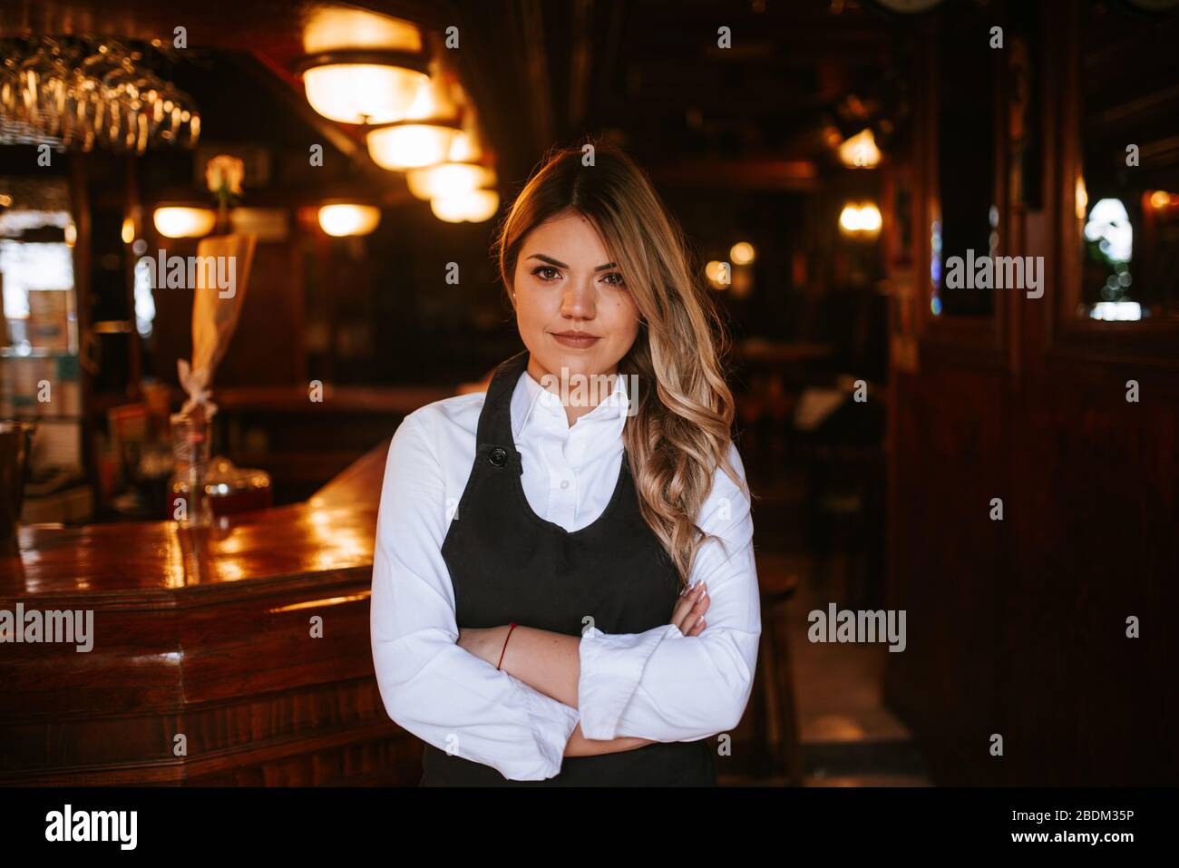 Portrait of young attractive caucasian blonde waitress at cafe entrance ...