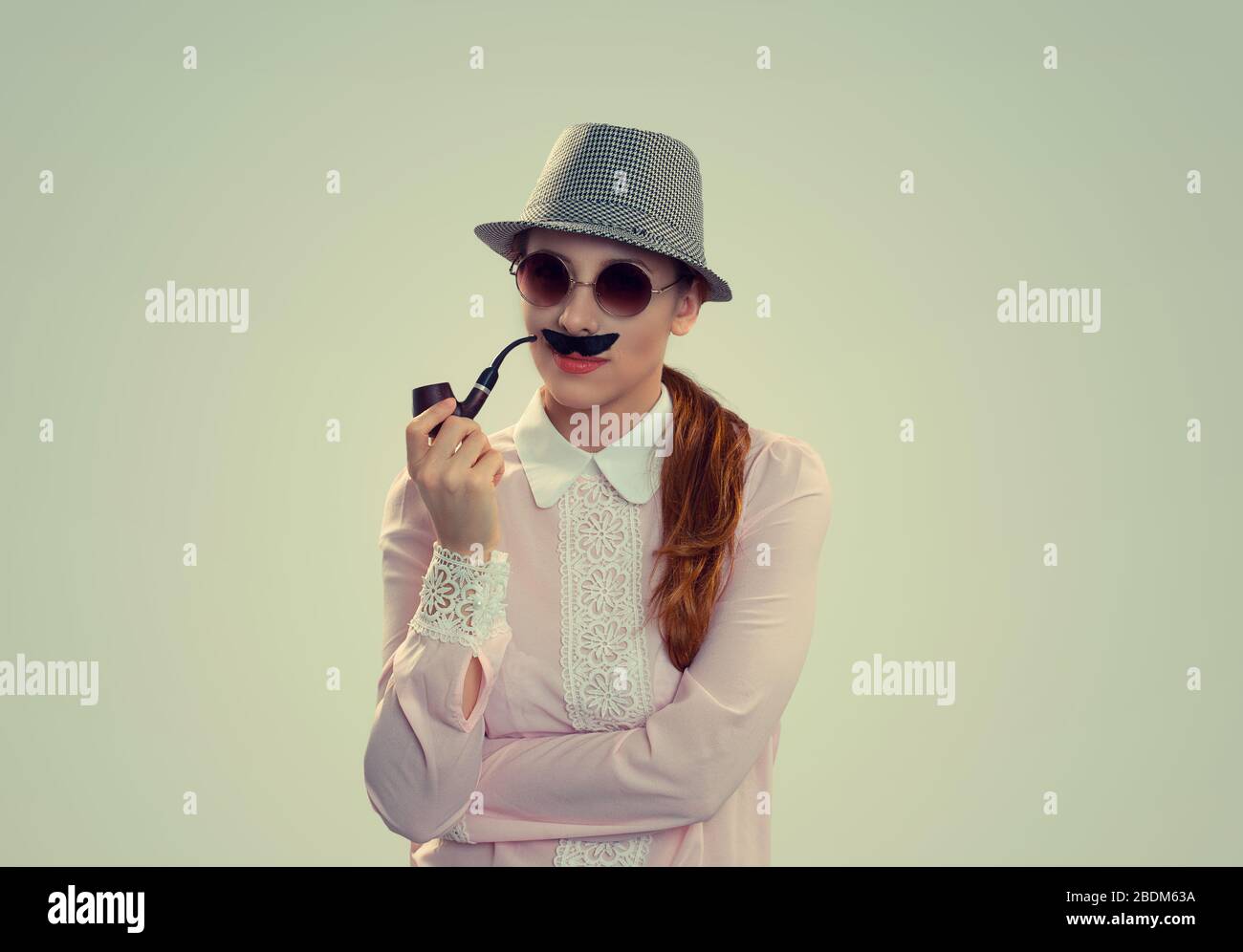 Woman with round glasses fake mustache, pipe and hat imitating man ...