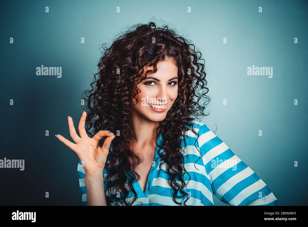 Beautiful young woman showing Ok sign isolated on blue wall background ...
