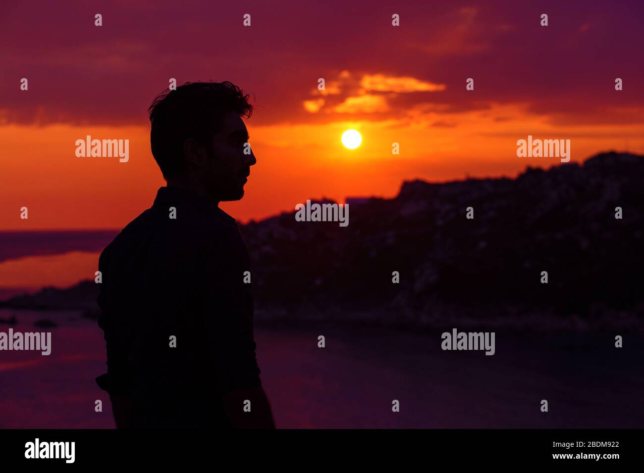 Young man is looking at the sunset thinking Stock Photo - Alamy