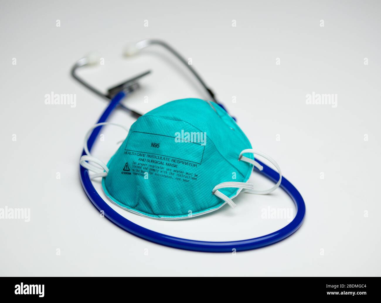An single teal N95 respirator mask on top of a blue medical stethoscope ...