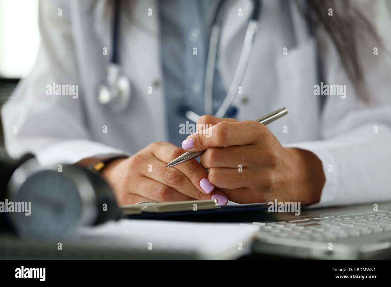 Arms of GP writing with silver pen document Stock Photo - Alamy