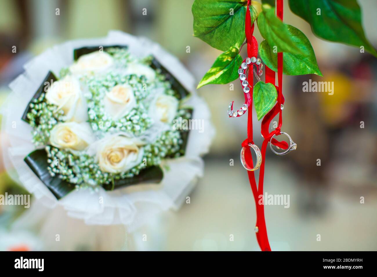 The rings hung from a red ribbon. Two wedding rings hung from a tree ...