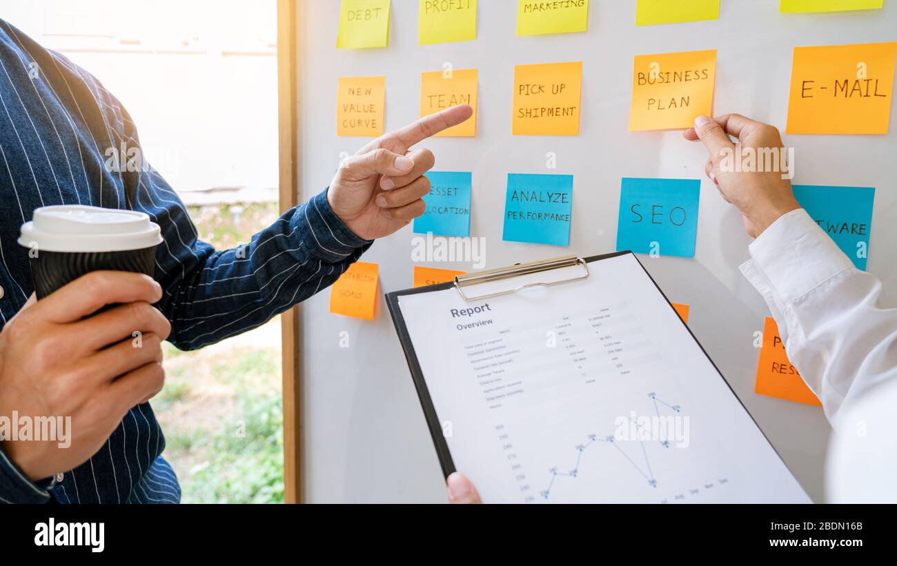 Business people arranging sticky notes commenting and brainstorming on ...
