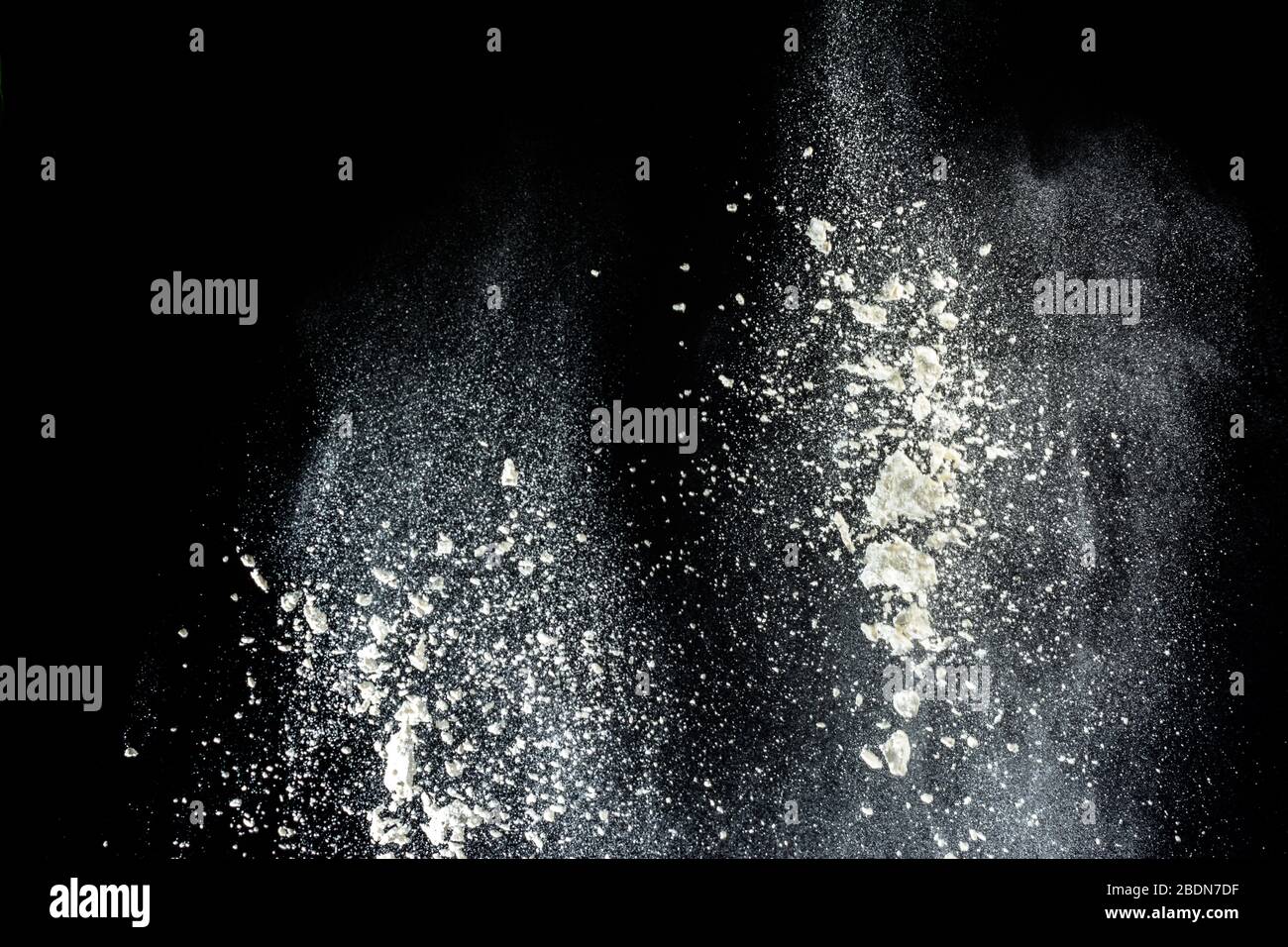 Burst of white powder with flour and sugar creating a beautiful pattern ...