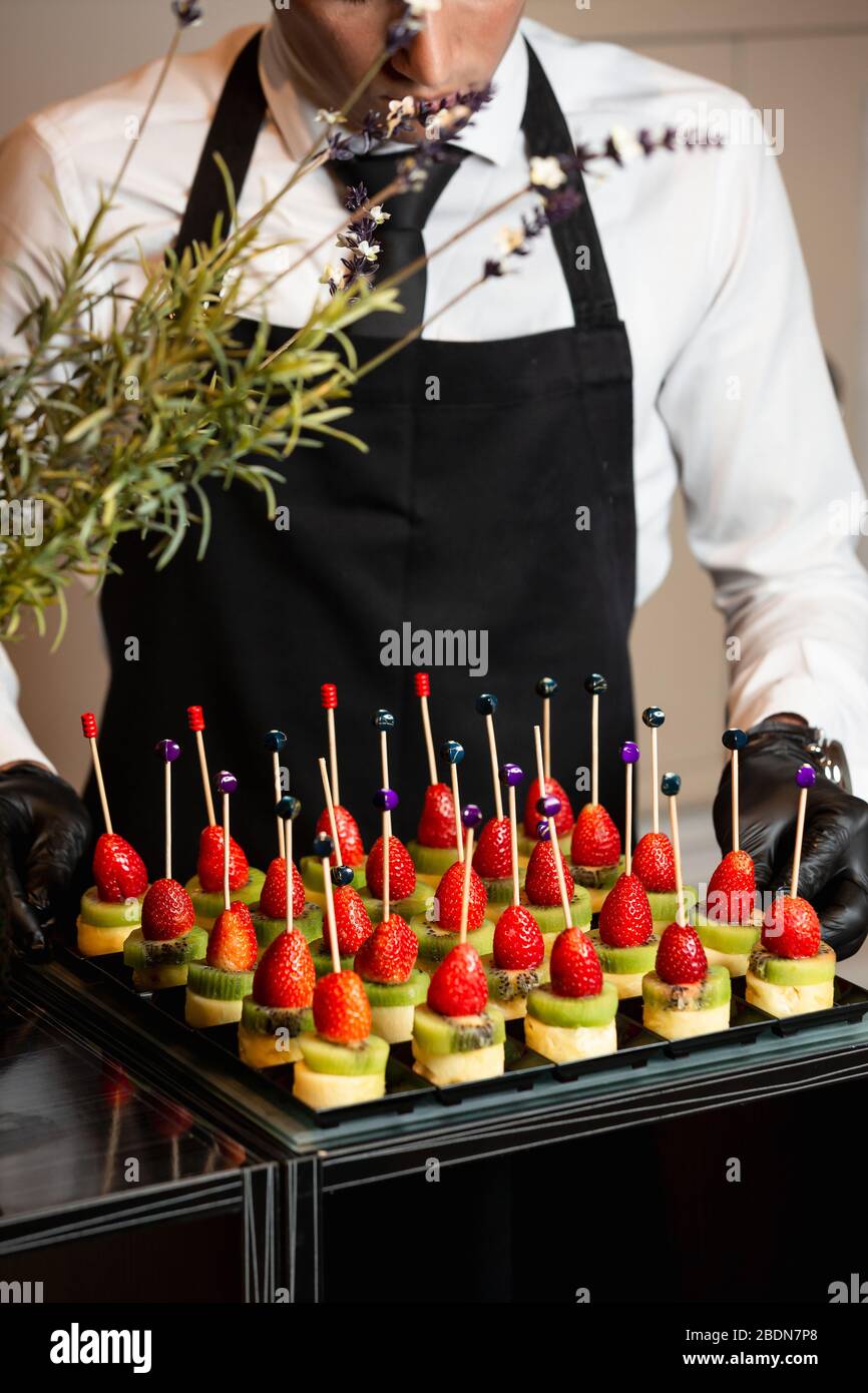 fruit delicacies on a tray in the hands of a waiter Stock Photo - Alamy