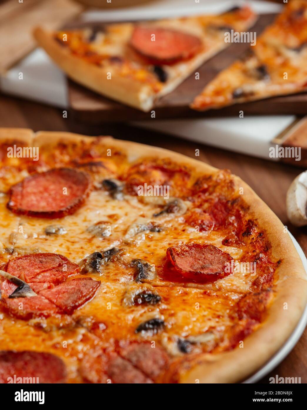 pizza with slices of pepperoni and mushrooms Stock Photo - Alamy