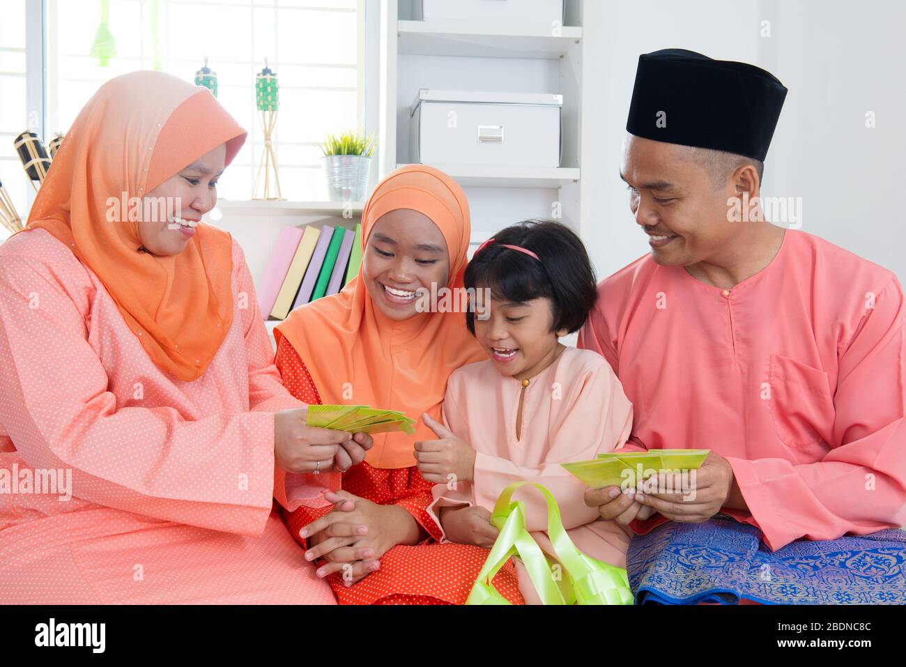 Woman giving green packet to the girls during hari raya. Malay or ...