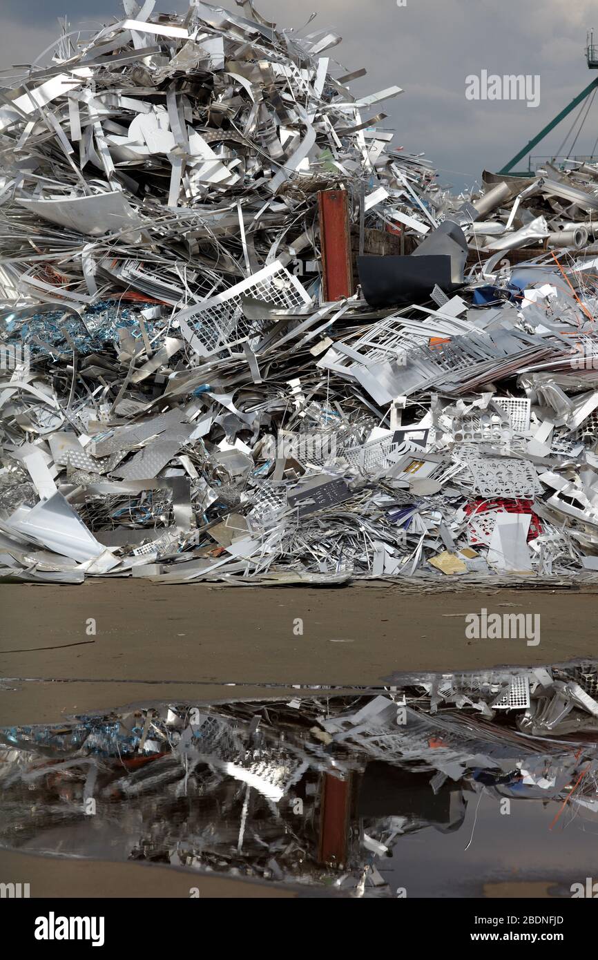 A large pile of metal in a scrap yard is reflected in a puddle Stock ...