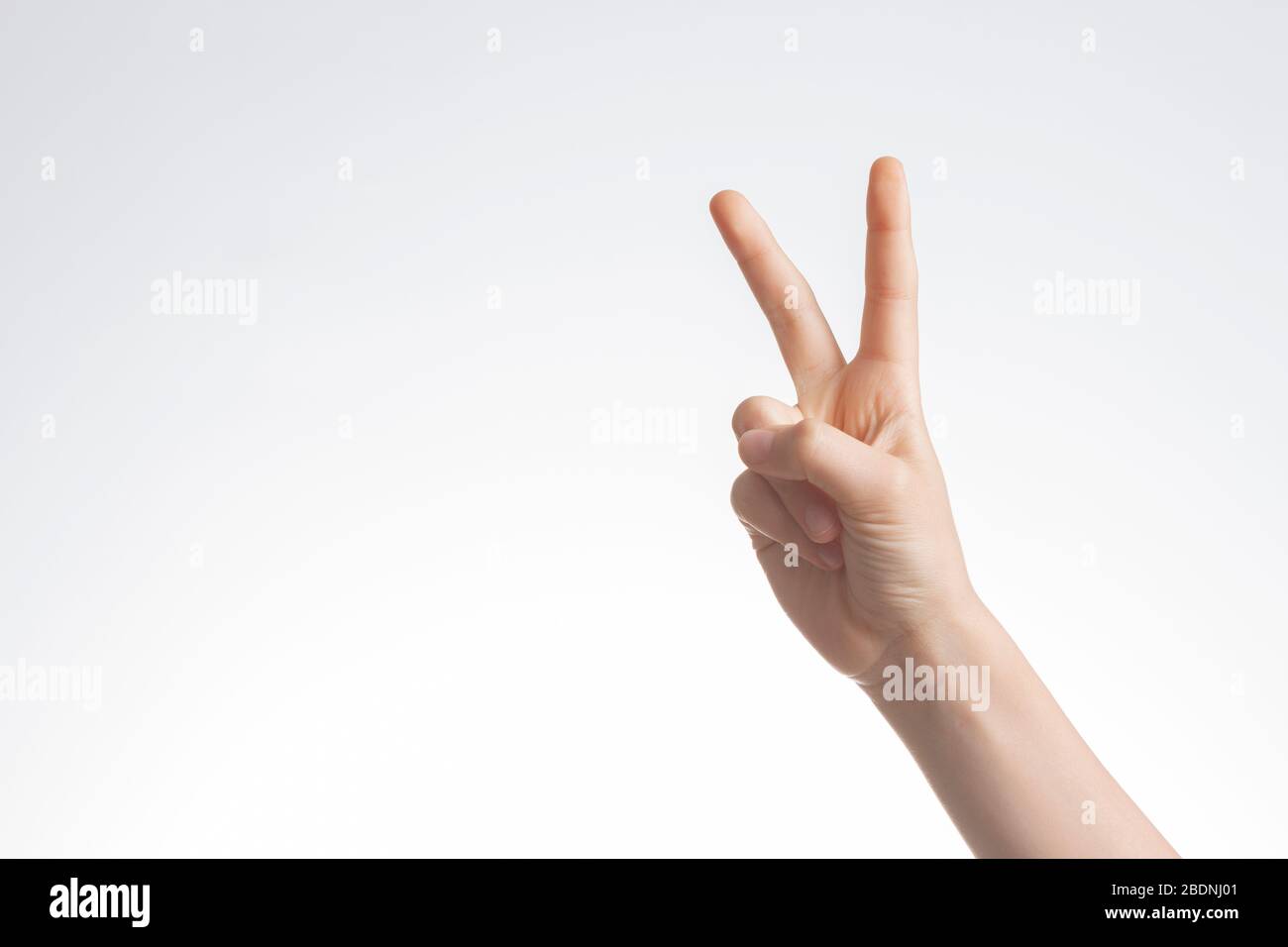 Kid hand shows victory gesture, point number two on white wall ...