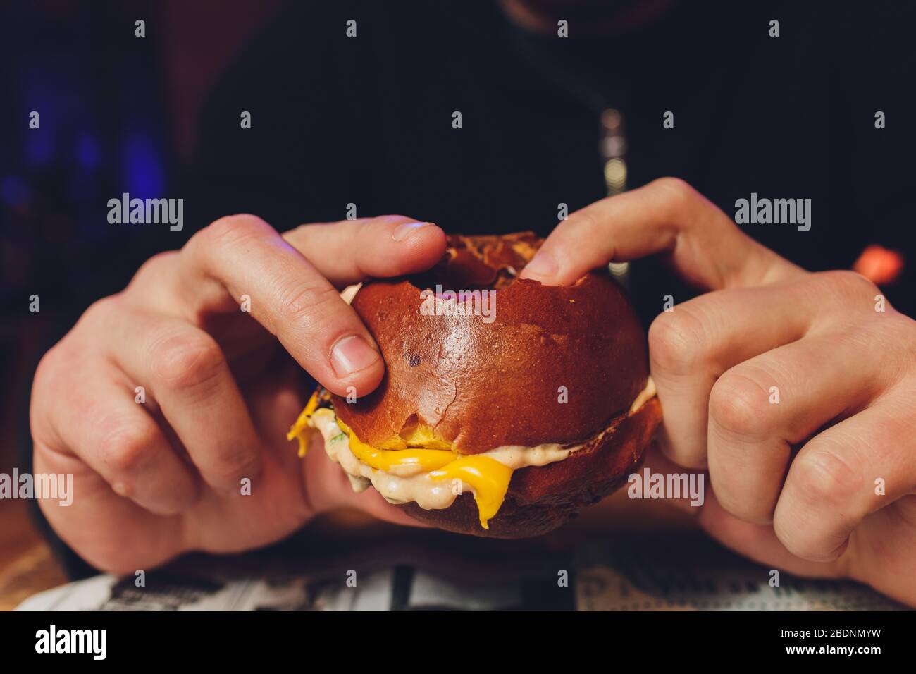 A bitten fresh burger in the hands of a man Stock Photo - Alamy