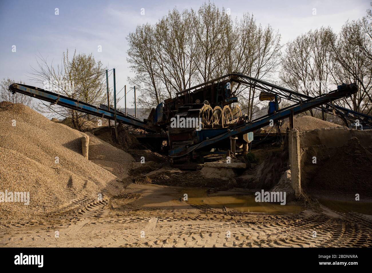 Machine sorting sand and gravel. Excavator and conveyer at the quarry ...