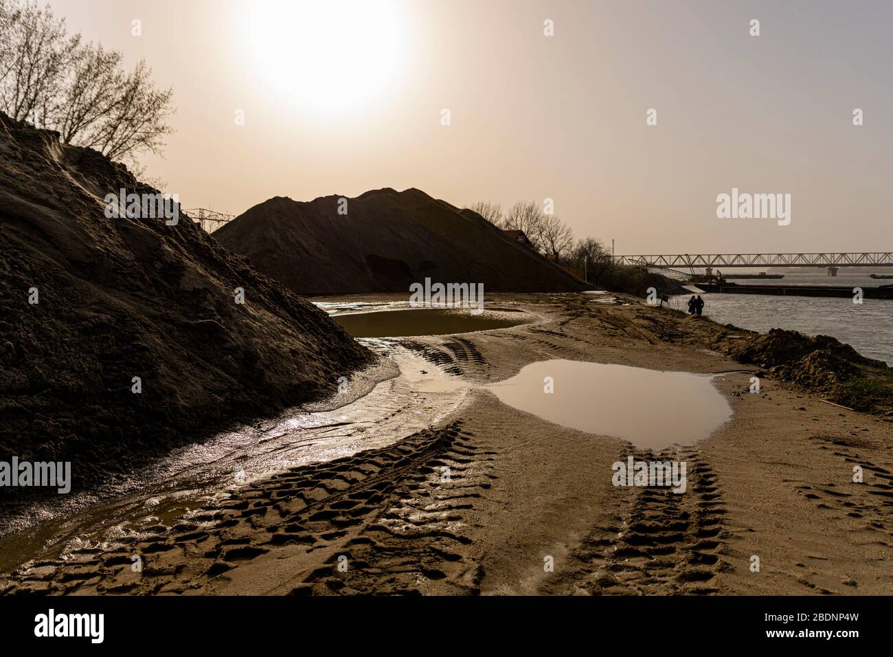 Excavator tracks in the sand with amazing sunset over the pile of ...