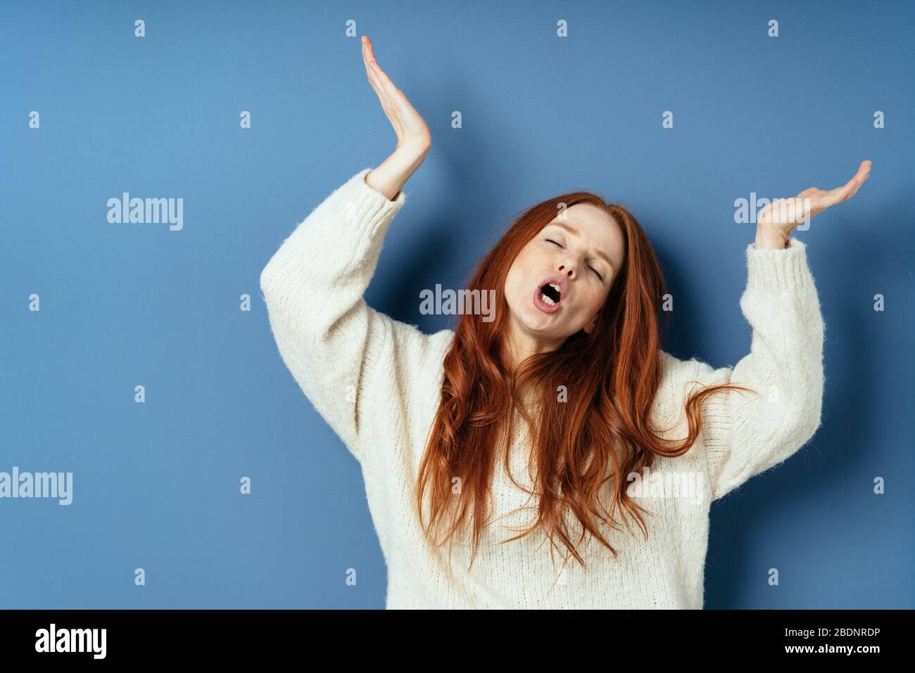 Happy young redhead woman singing with a blissful expression and eyes ...