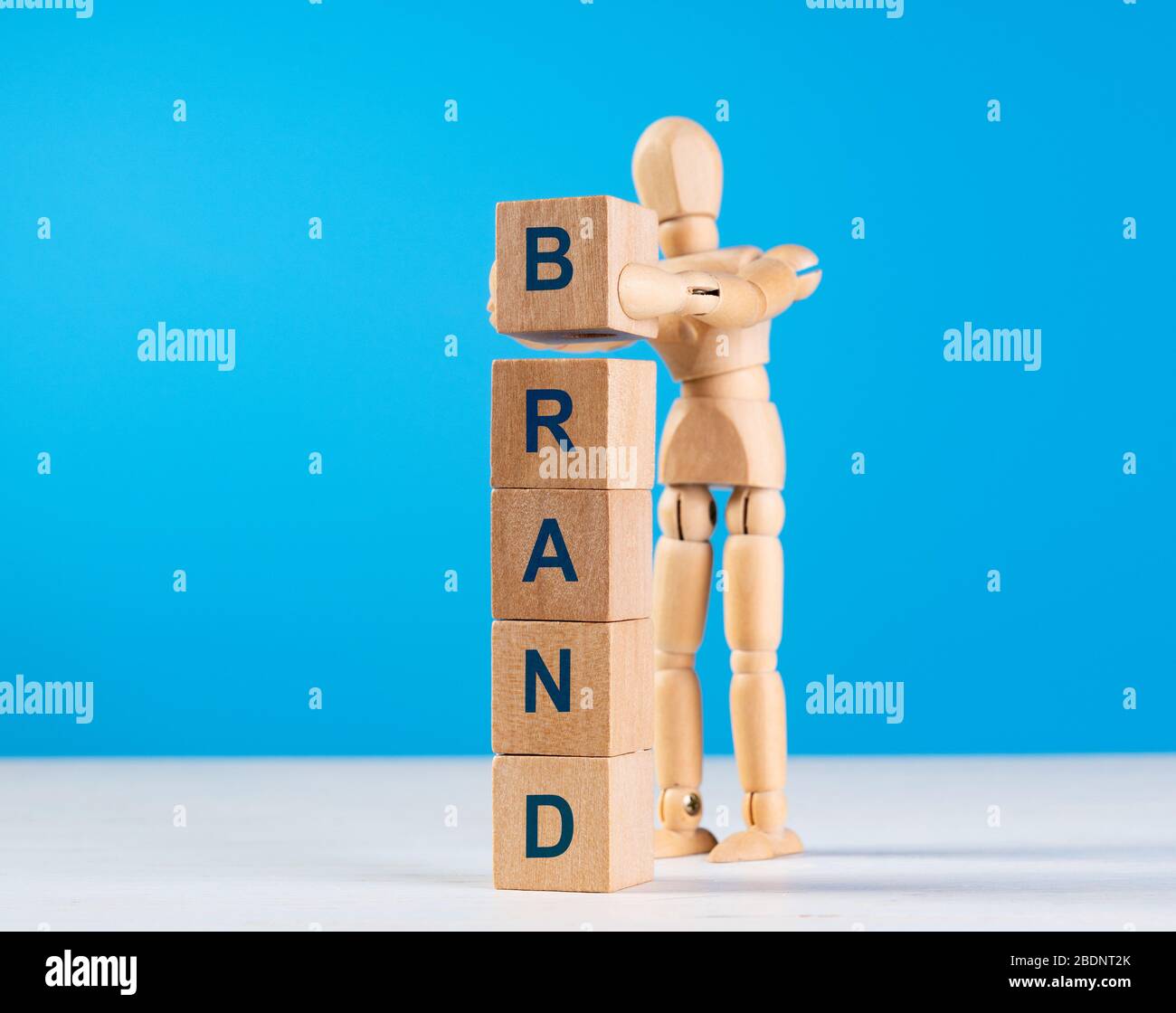 Wooden man construct tower with blue word BRAND. Mannequin put last ...