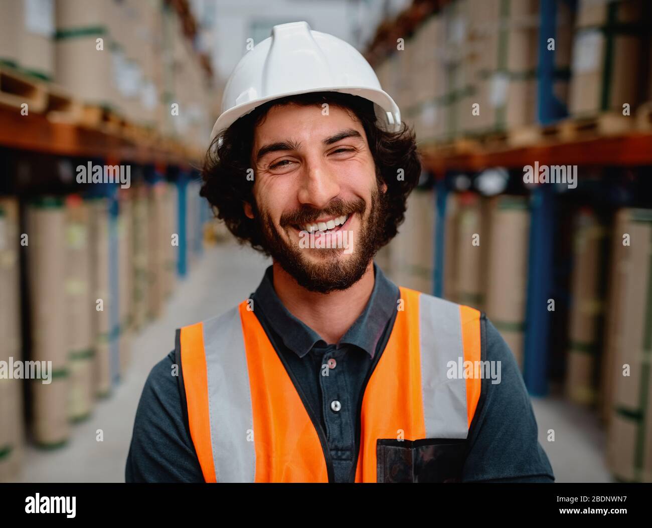 Portrait of happy male worker in warehouse wearing orange vest and ...