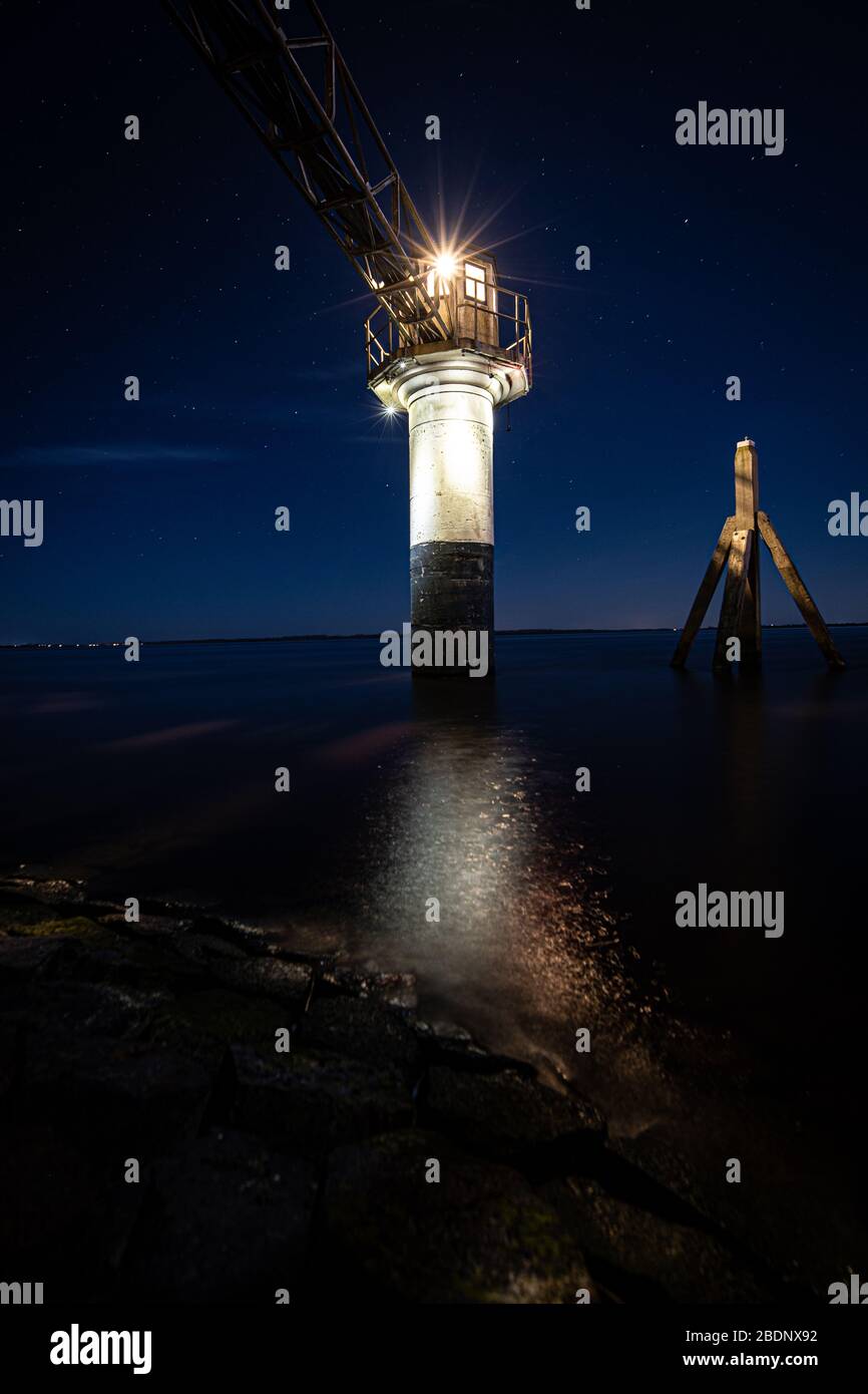 Harbor and historical nautical light tower during nightfall under a ...