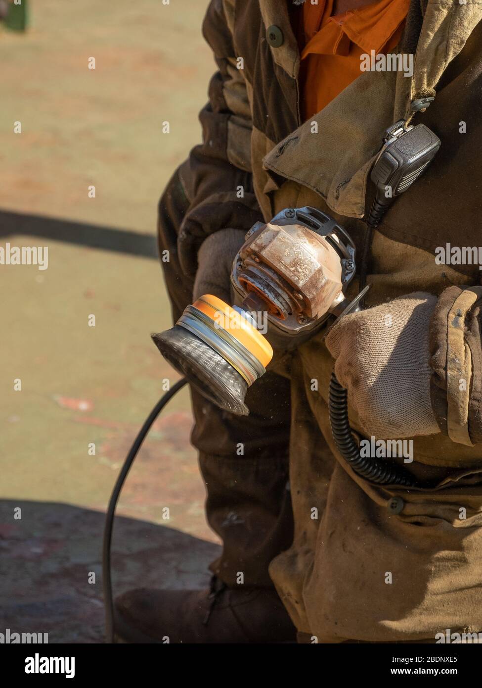 A worker in dirty overalls works with a grinder Stock Photo - Alamy