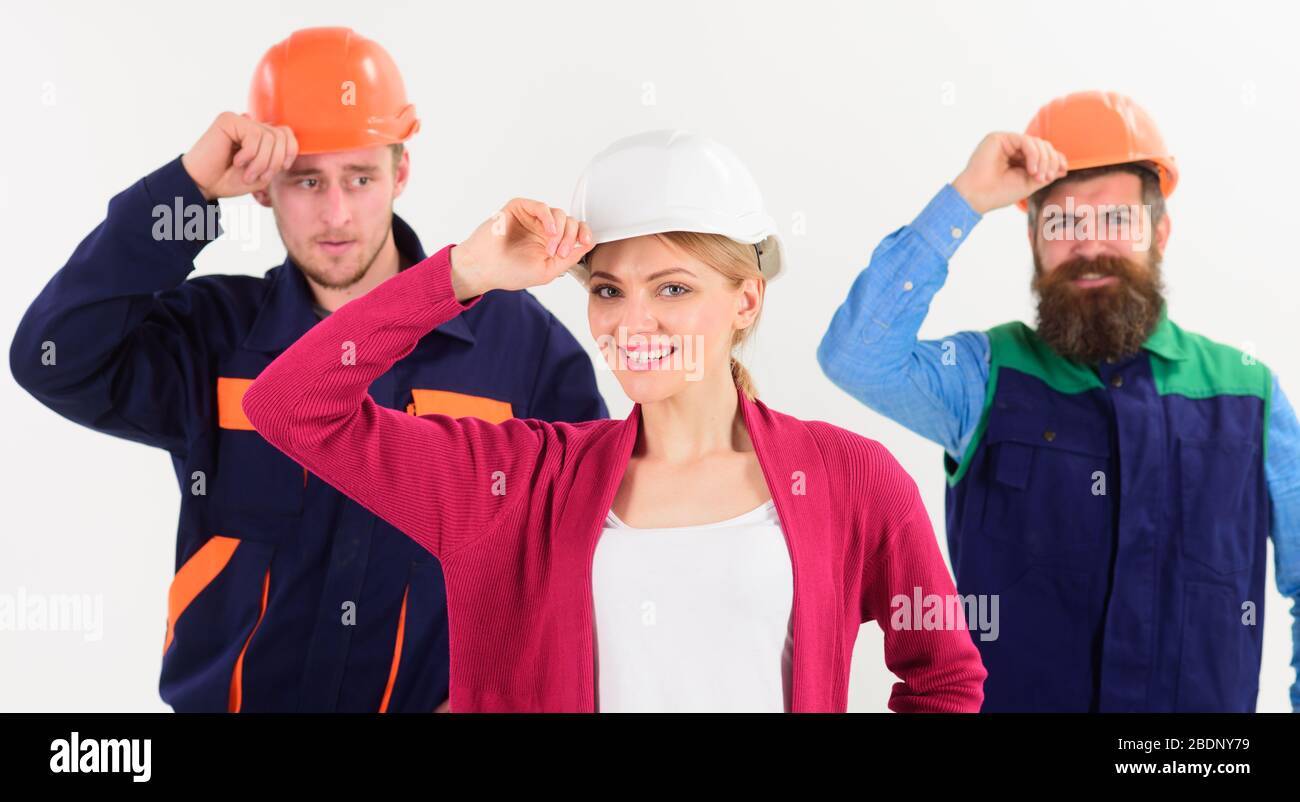team work concept - two young men and woman in builders uniform and ...