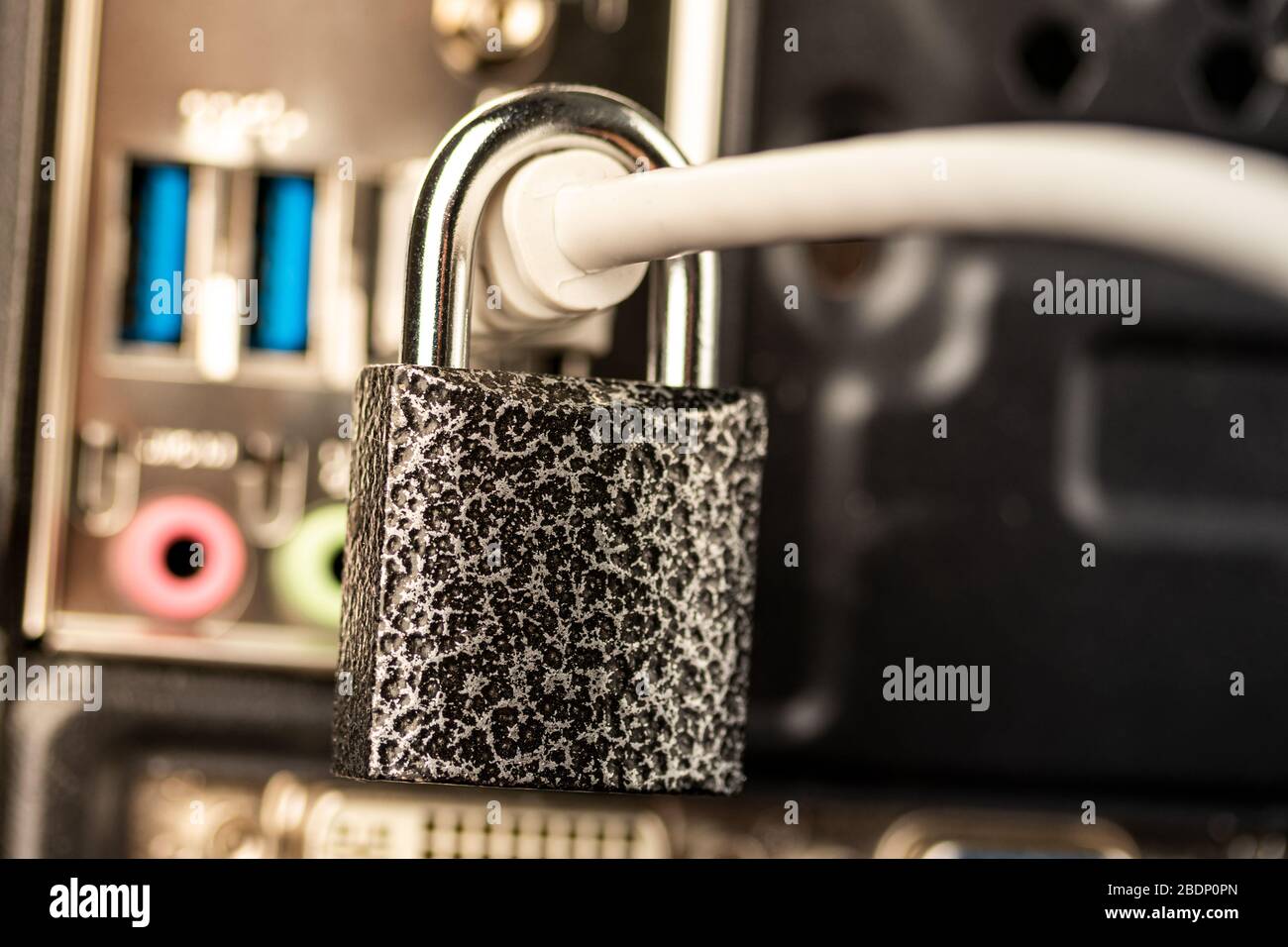 Closed lock hanging on a network cable plugged into a computer. The ...
