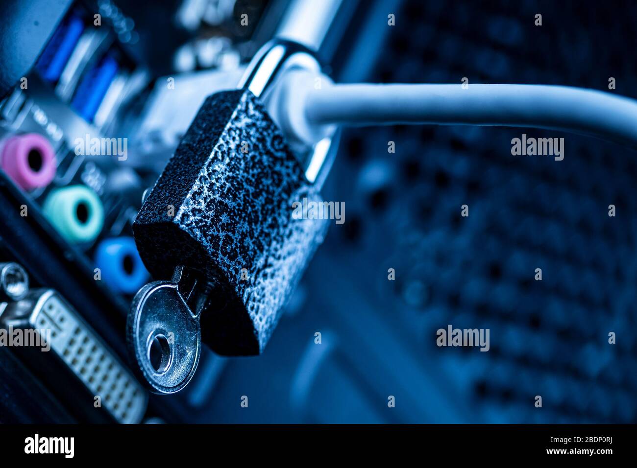Closed lock hanging on a network cable plugged into a computer. The ...