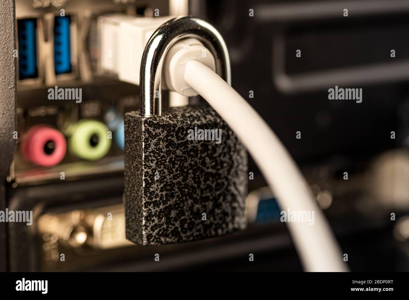 Closed lock hanging on a network cable plugged into a computer. The ...