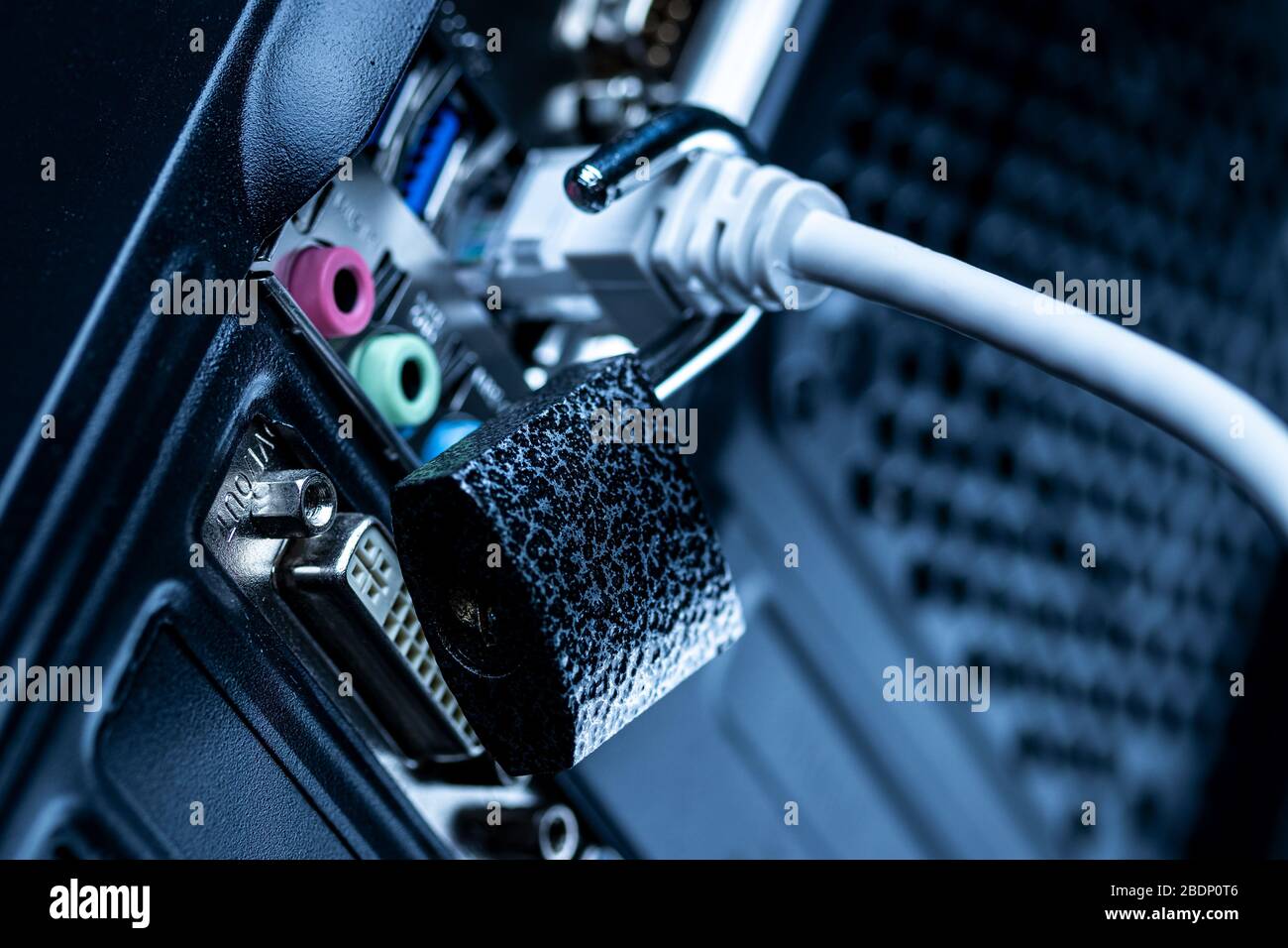 Opened lock hanging on a network cable plugged into a computer. The ...
