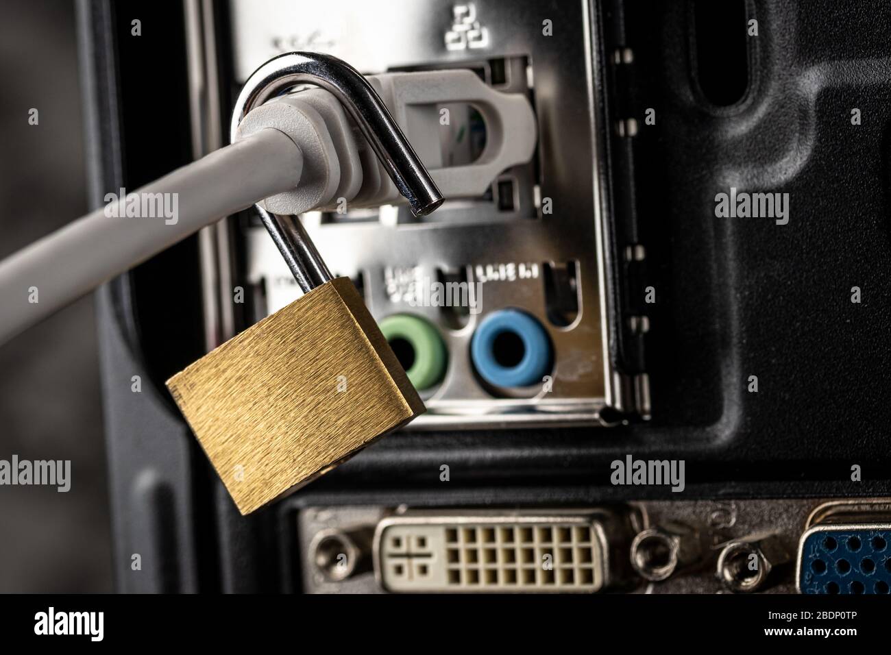 Opened lock hanging on a network cable plugged into a computer. The ...