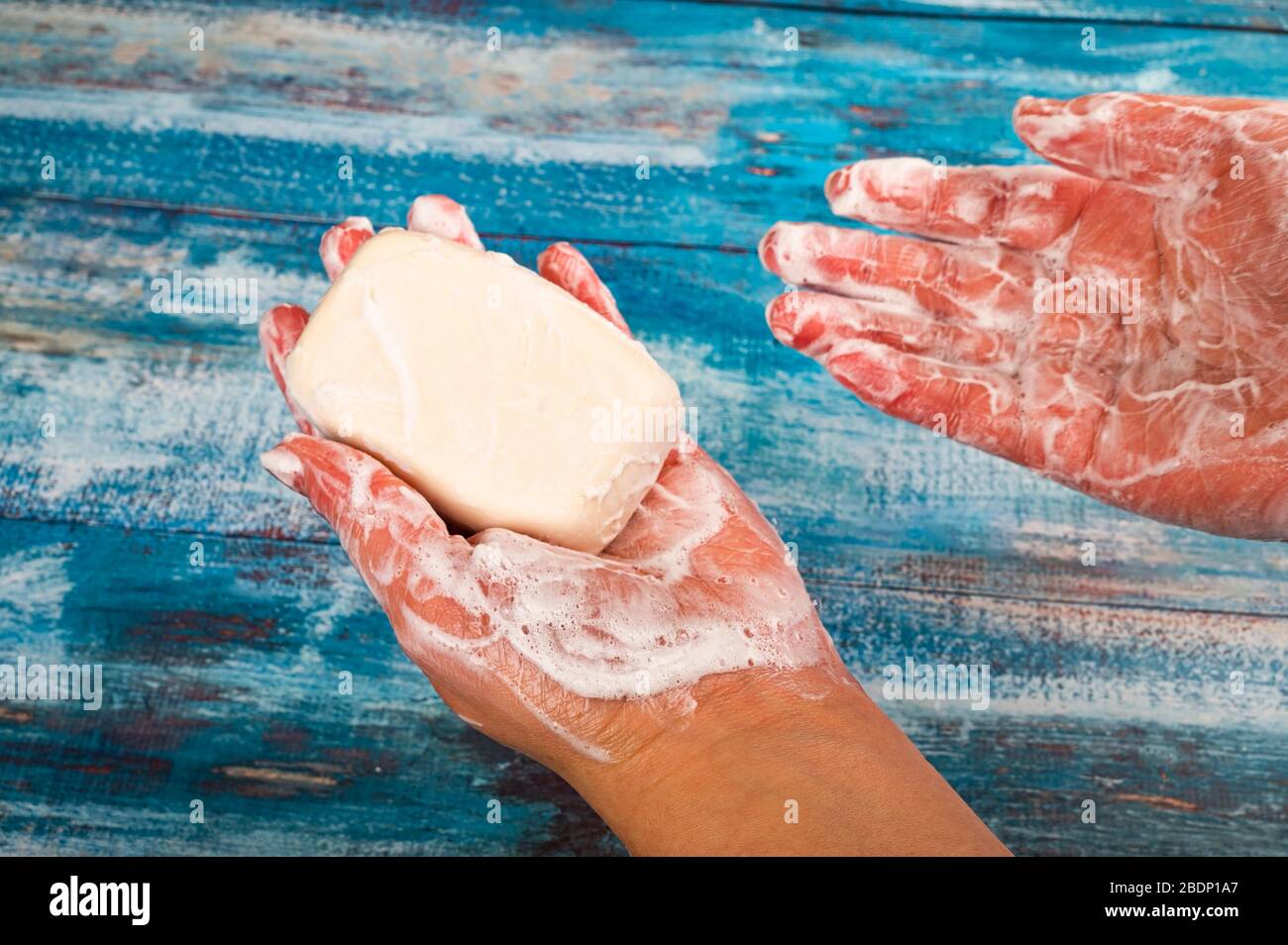 Someone is soaping their hands with a piece of toilet soap on a wooden ...