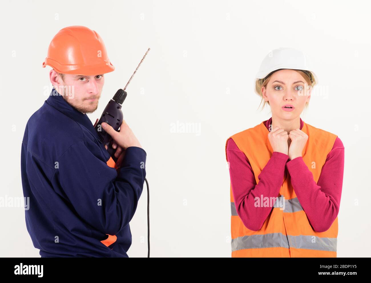 Woman with scared face in helmet, hard hat. Man with drill tool near ...