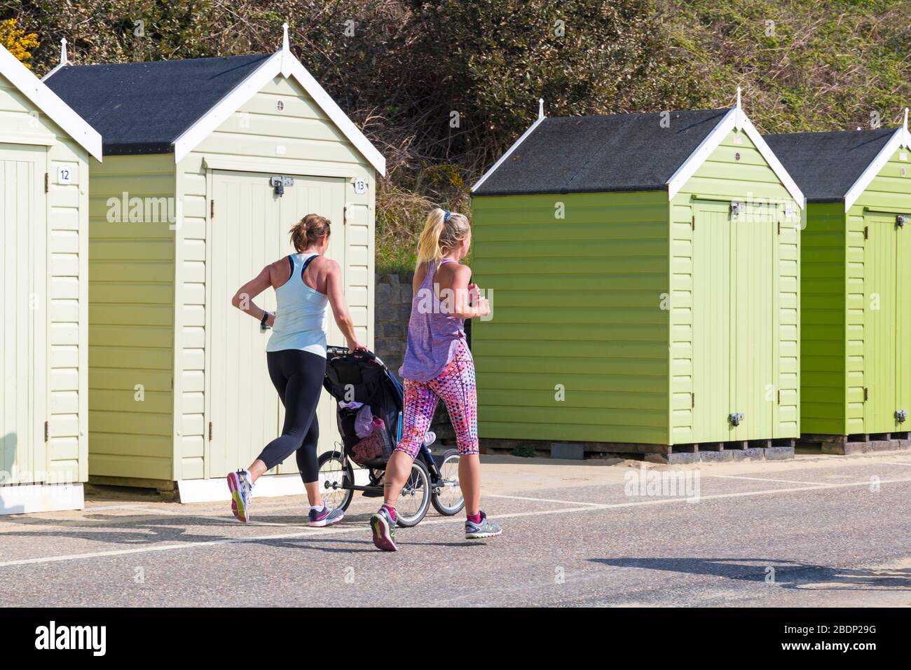 Lady jogging past beach huts hi-res stock photography and images - Alamy