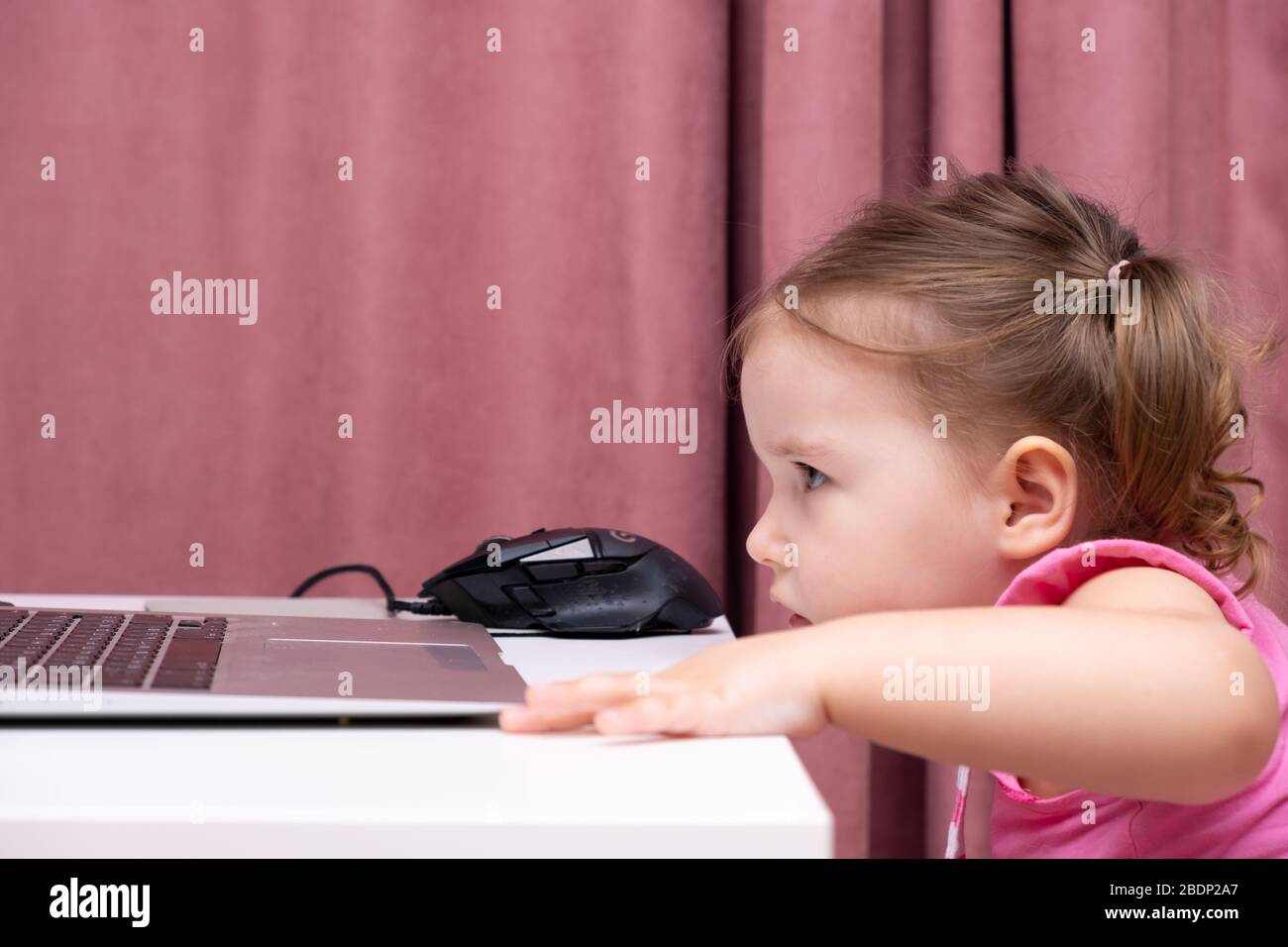 Beautiful cute sad little girl at a laptop. The concept of the ...
