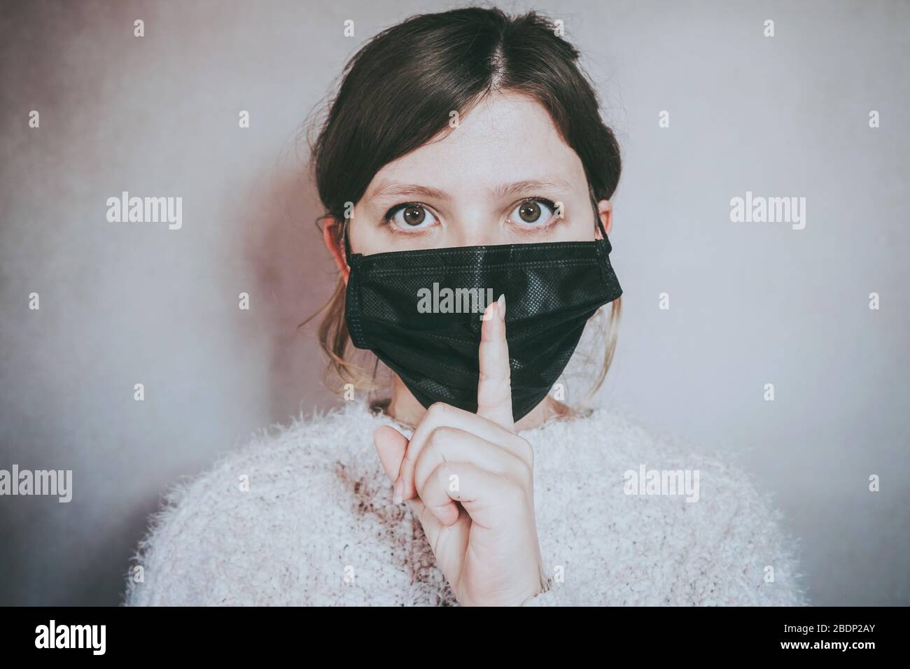 Young woman wearing a black mask and asking for silence Stock Photo - Alamy