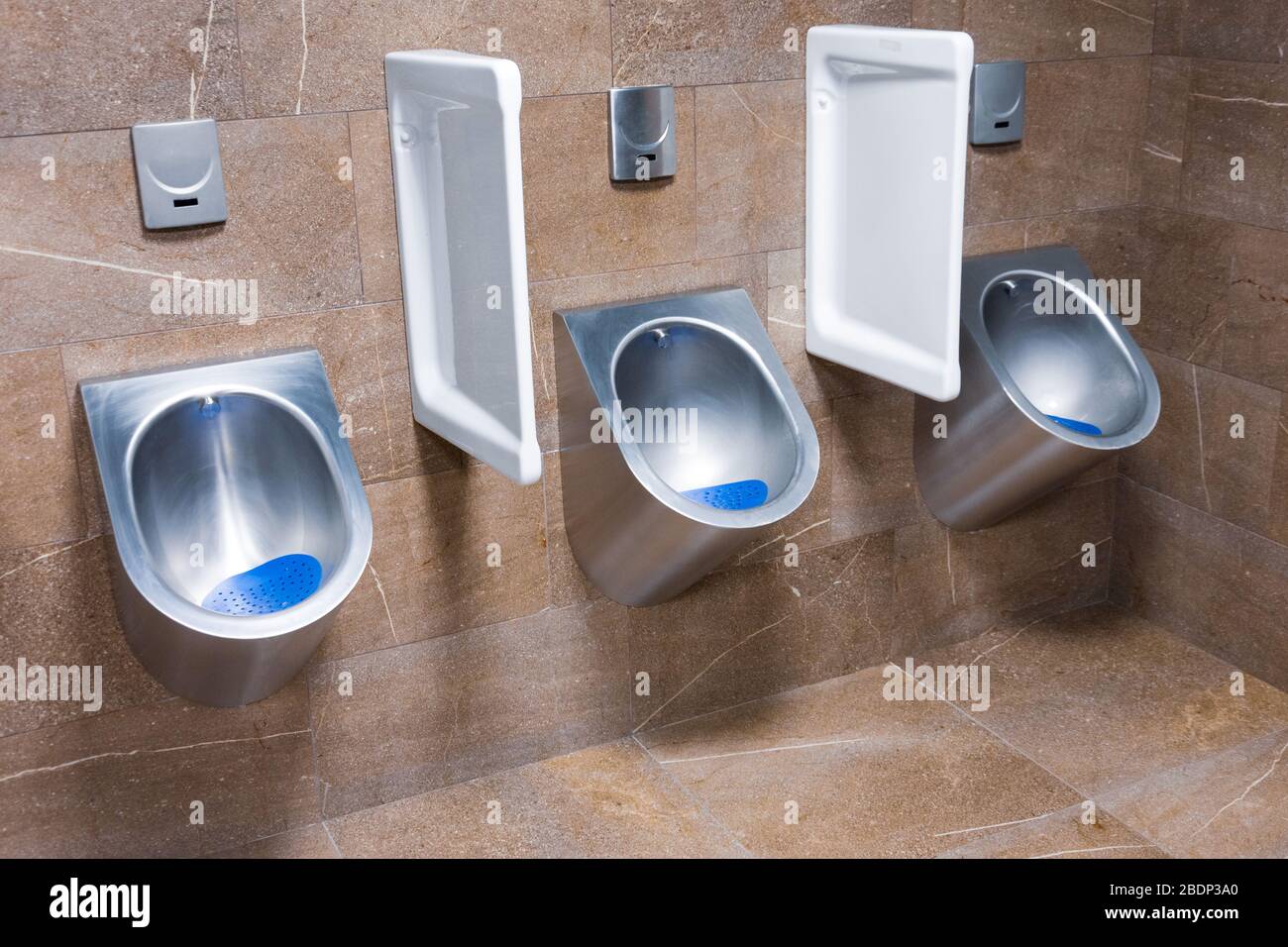 Three metal urinals with automatic water flush sensor after urinate ...
