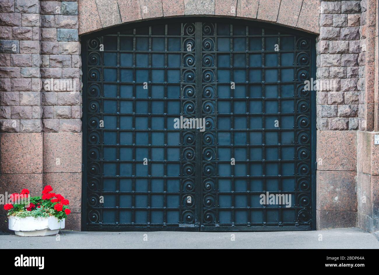 Closed forged gate at christian catholic church and red flowers in ...