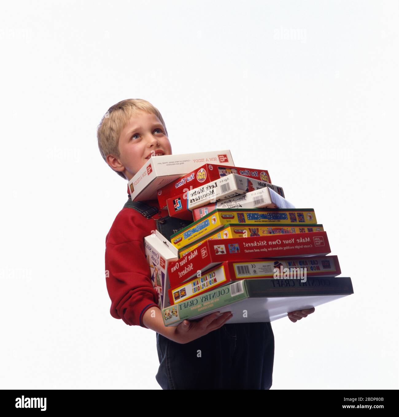 Boy carrying big pile of games and books FOR EDITORIAL USE ONLY ...