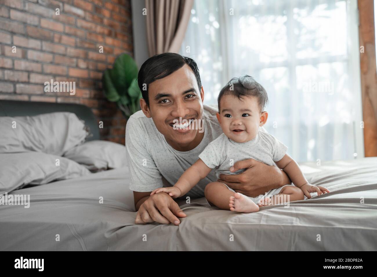 father bonding with baby. man playing with his daughter on the bed ...