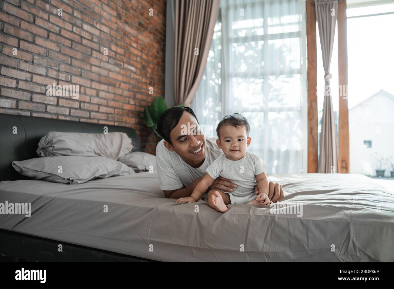 father bonding with baby. man playing with his daughter on the bed ...