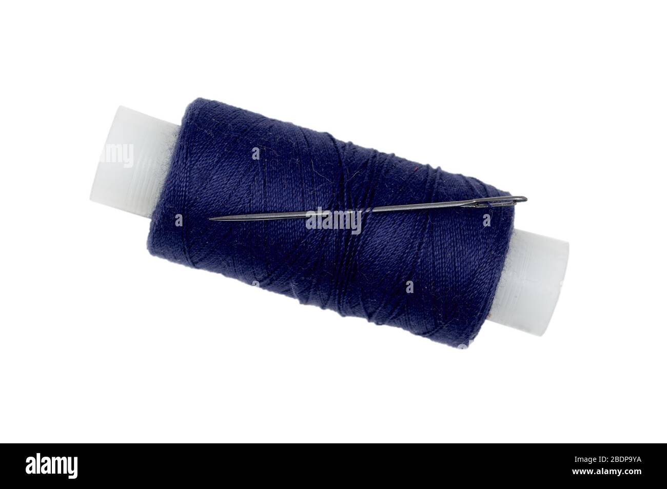 Close-up of spool of blue sewing thread with steel needle over white ...