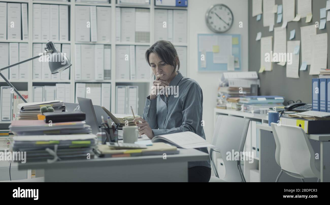 Efficient female office clerk sitting at desk in the office and working ...