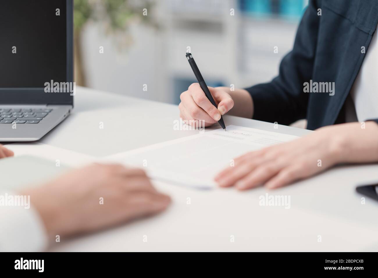 Business people meeting in the office, a woman is signing a contract ...
