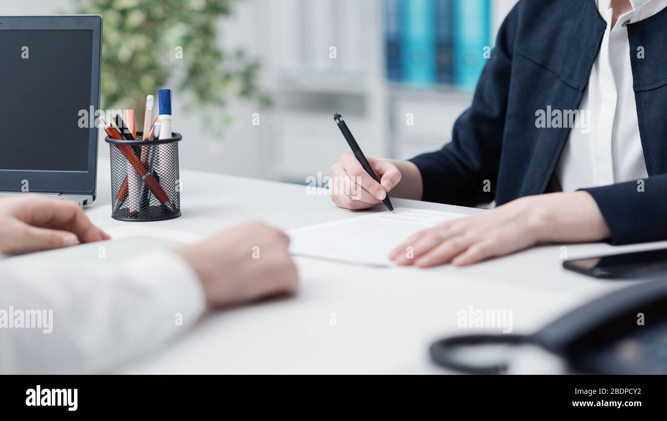 Business people meeting in the office, a woman is signing a contract ...