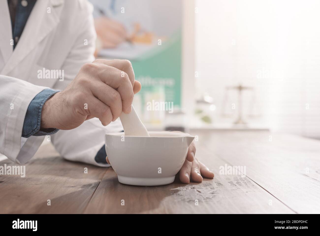 Professional pharmacist grinding a medical preparation using a mortar ...