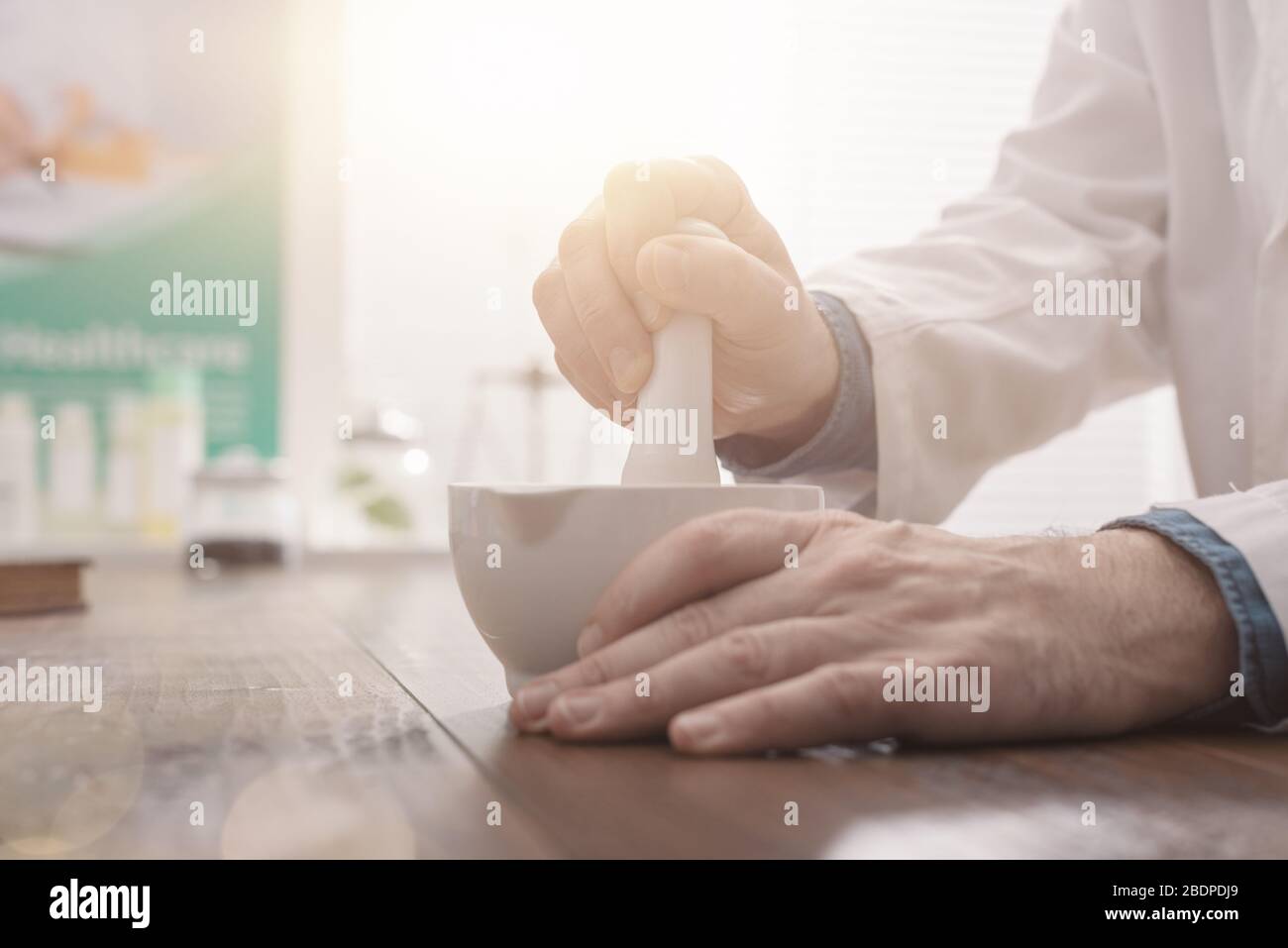 Professional pharmacist grinding a medical preparation using a mortar ...