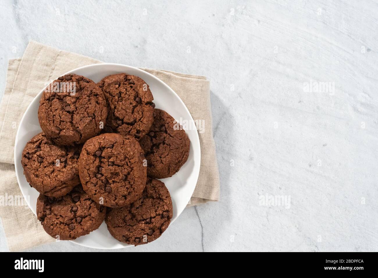 Flat lay. Freshly baked double chocolate chip cookies on a white plate ...