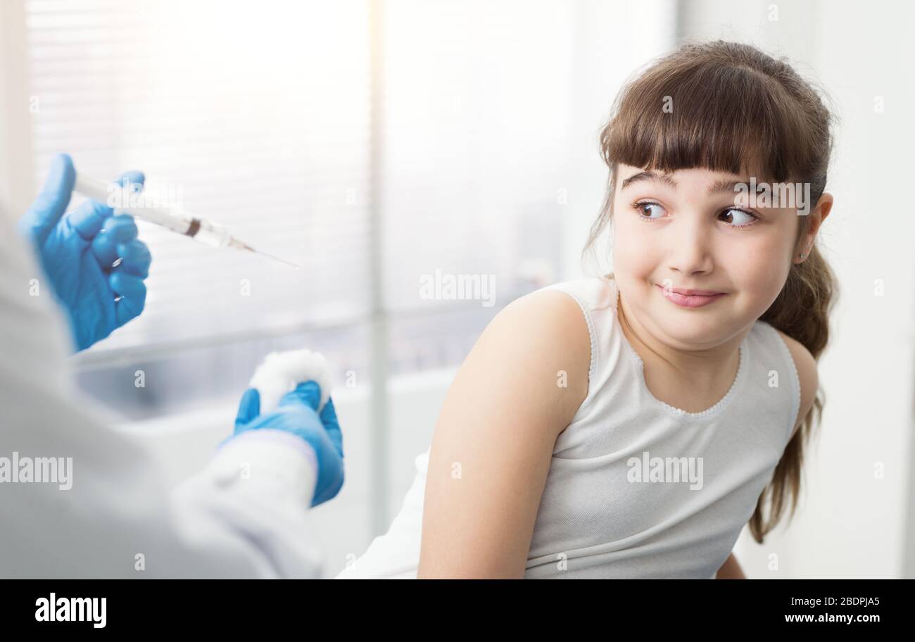 Doctor giving an injection to a scared child, the girl is frightened ...